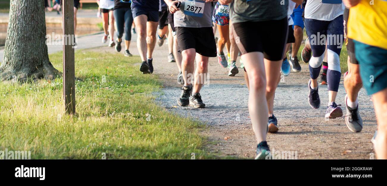 Legs of a large group of runners running a 5K race on a dirt path ...