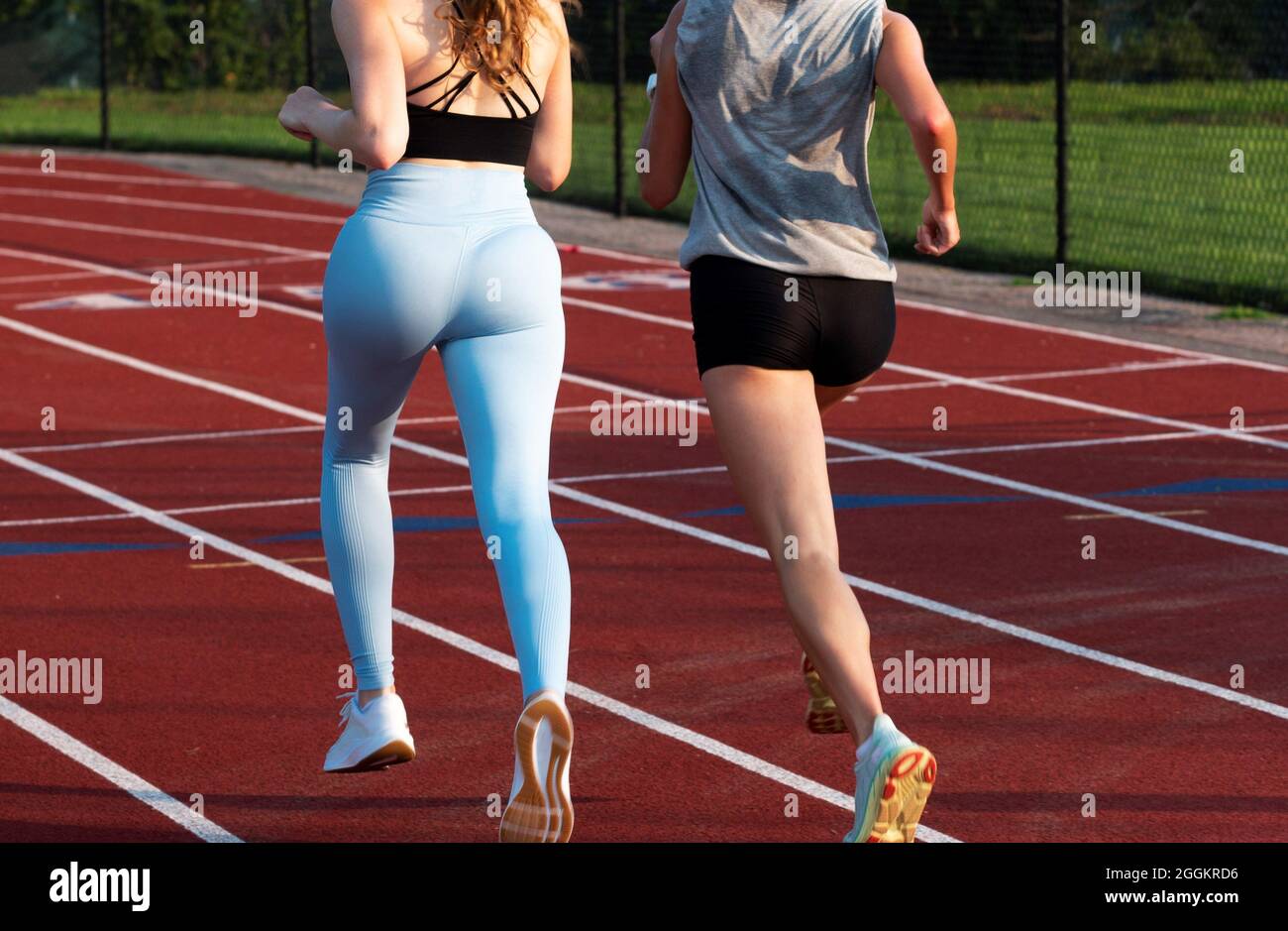 Rear view of two college girls training together on a track for track ...