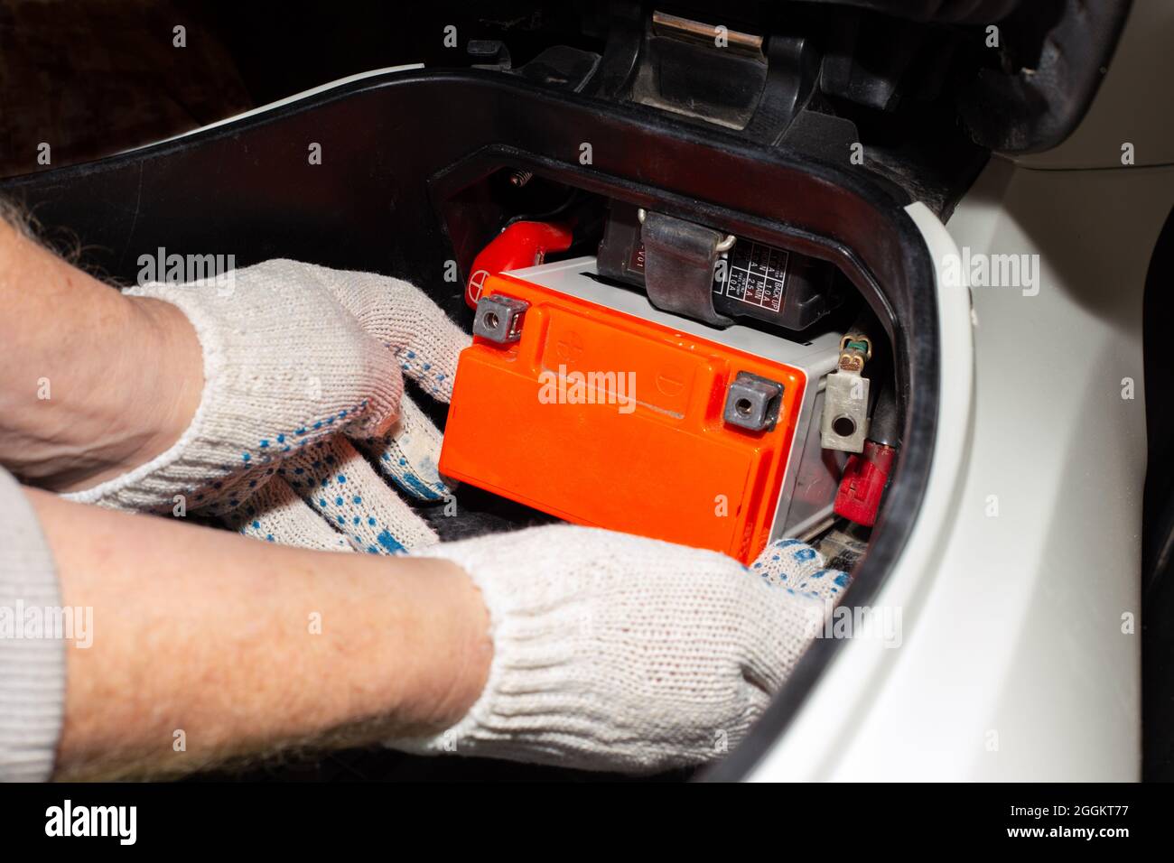 Replacing the motorcycle battery. An auto mechanic in a car service ...