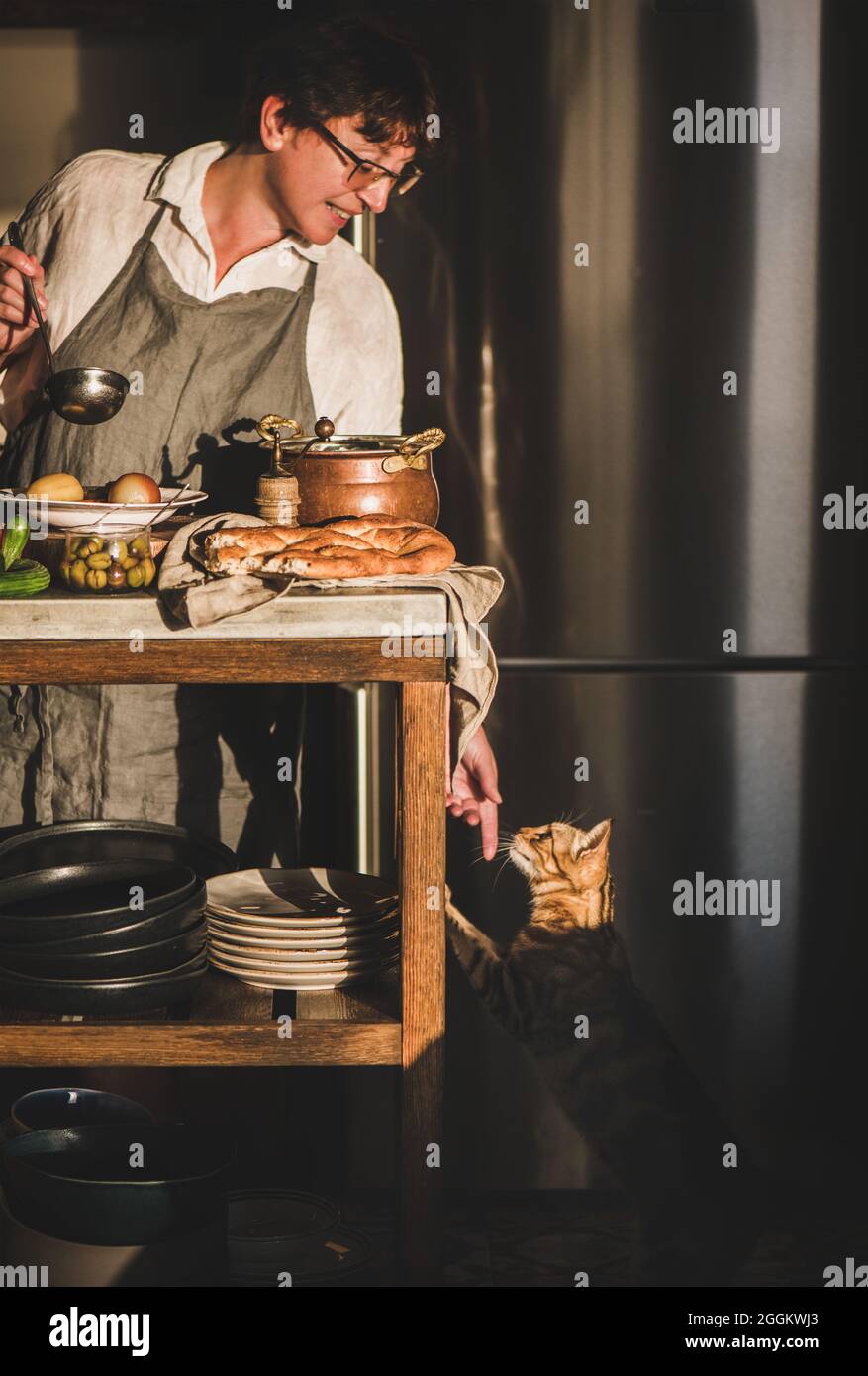 Woman cooking Turkish traditional meat soup Haslama and touching cat ...