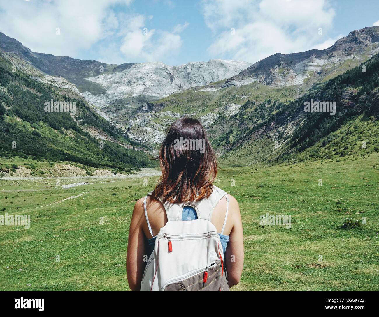 Back view of a female backpacker observing the beautiful green ...