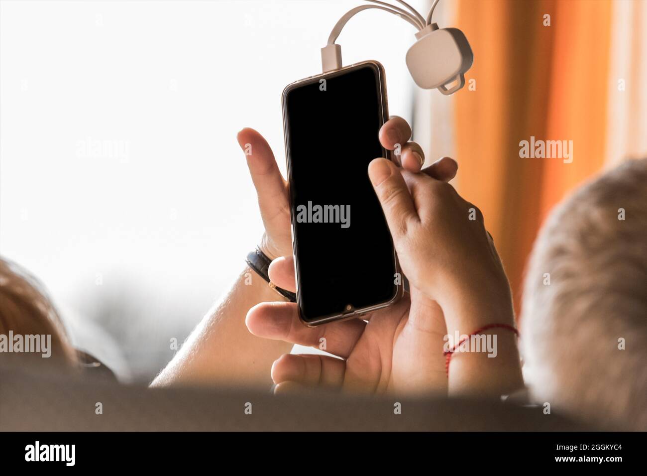 A woman holds and charges a phone on the bus using a modern USB charger ...