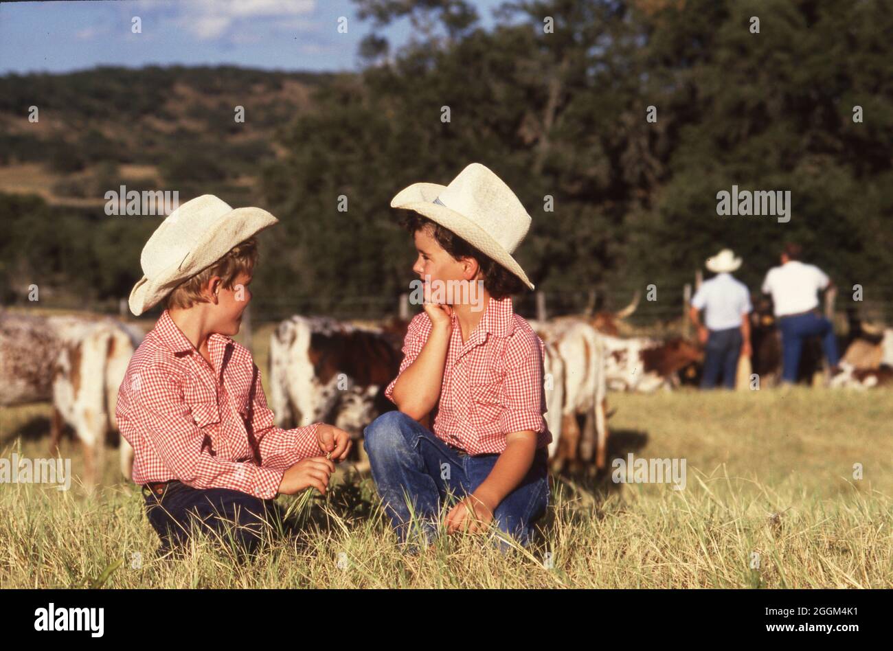 Stonewall Texas USA, 1989 Young boys wearing cowboy hats sit in pasture ...