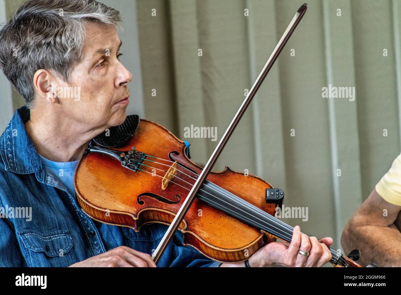 A senior lady plays the fiddle in the Mid-Day Mountain Music bluegrass ...