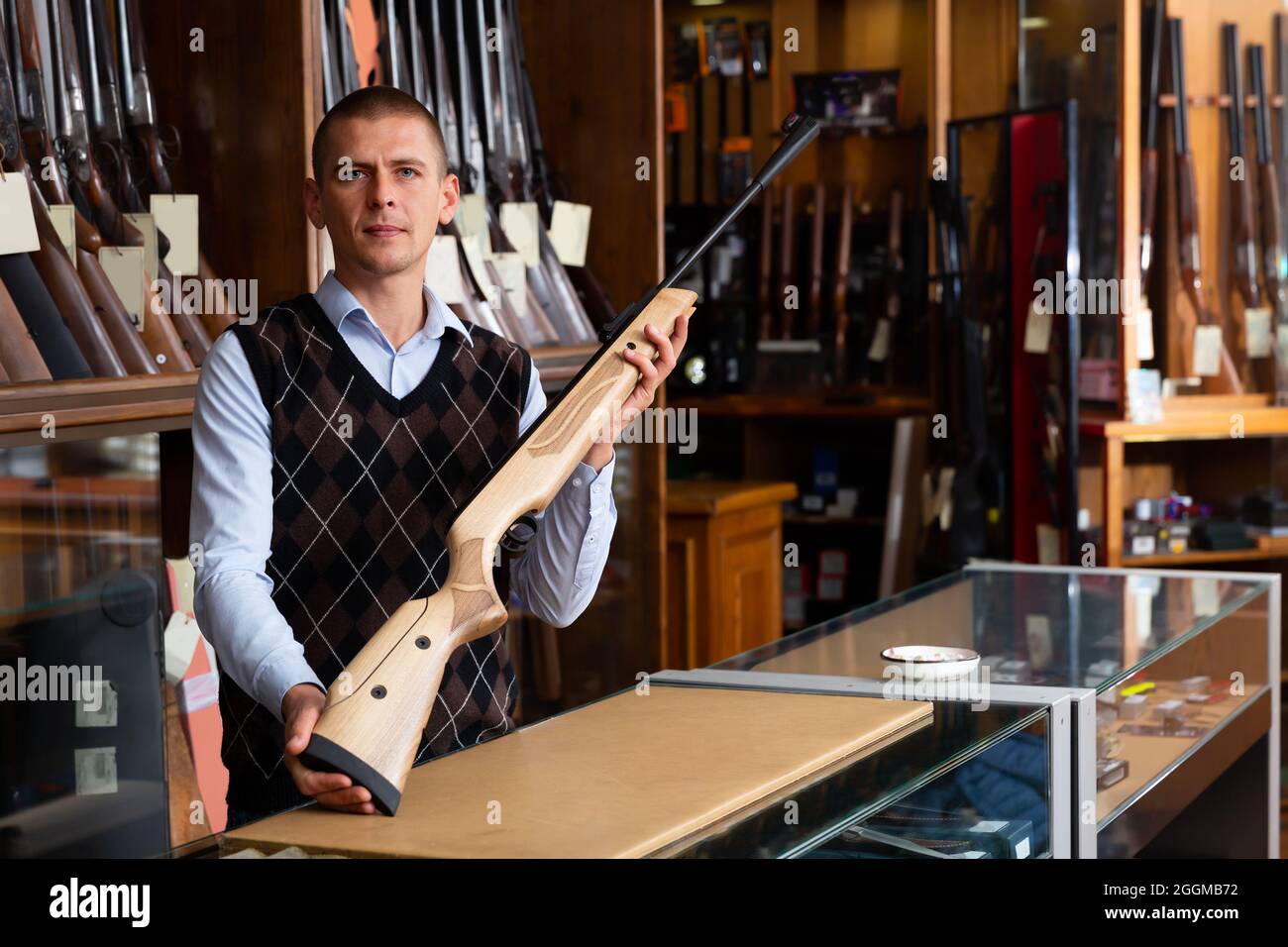 Gun shop salesman with air rifle in hand closeup Stock Photo - Alamy