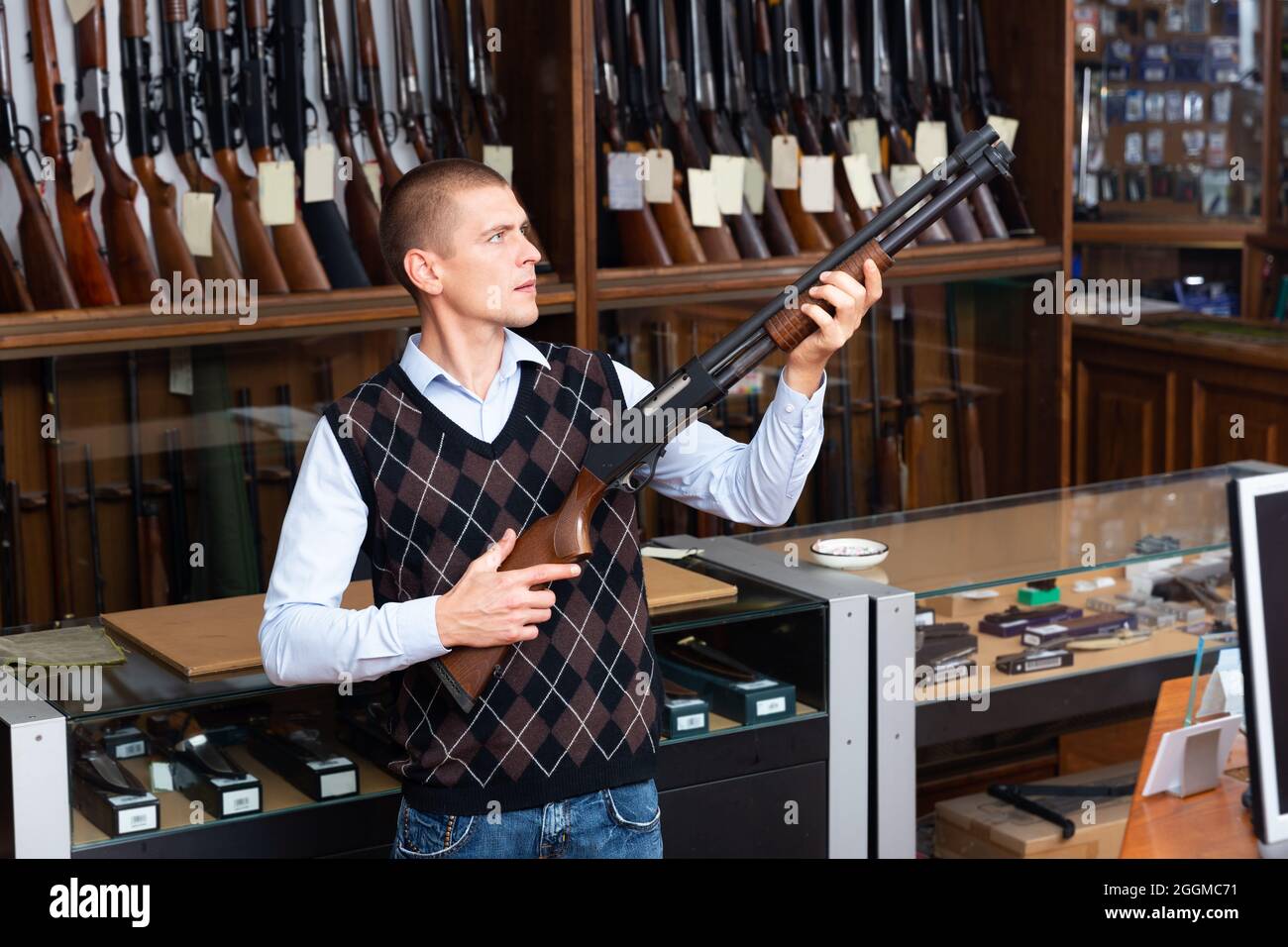Man examining pump action hunting rifle in gun shop Stock Photo - Alamy