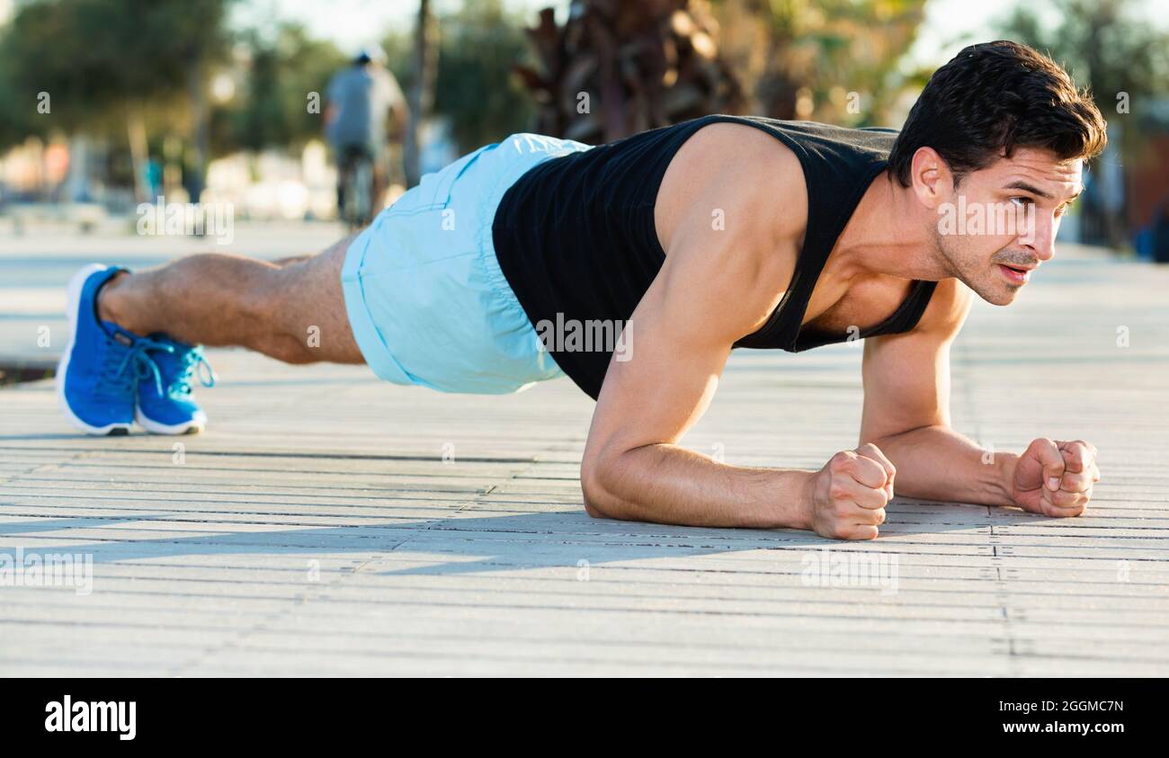 Strong sporty man doing press exercises holding plank outdoors Stock ...