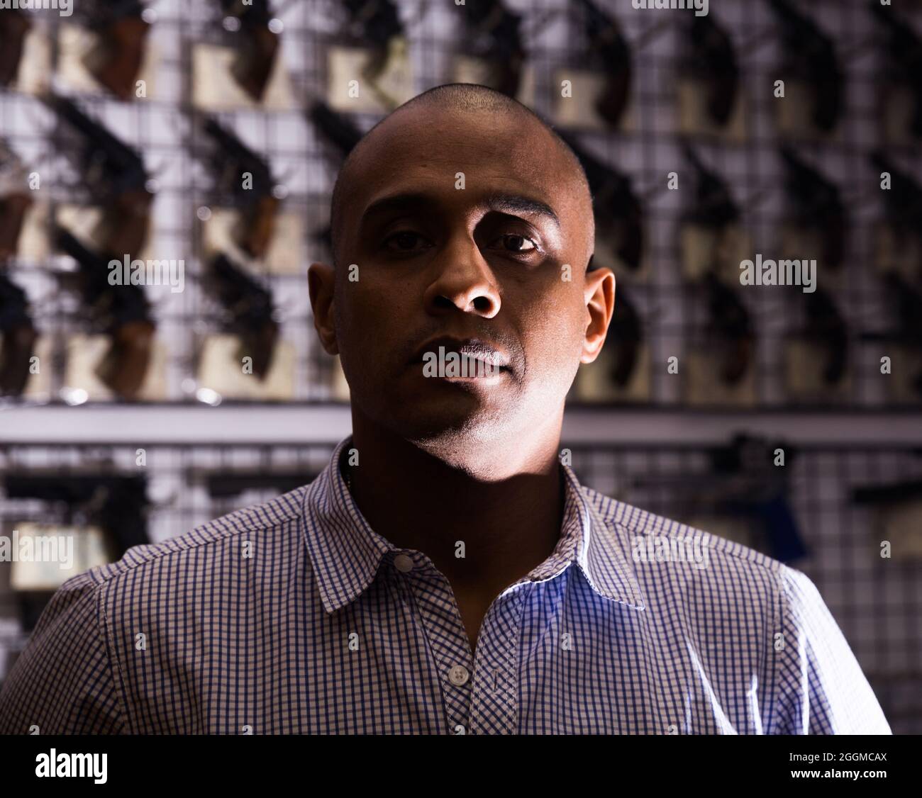 Confident hispanic man in dark room of gun shop Stock Photo - Alamy