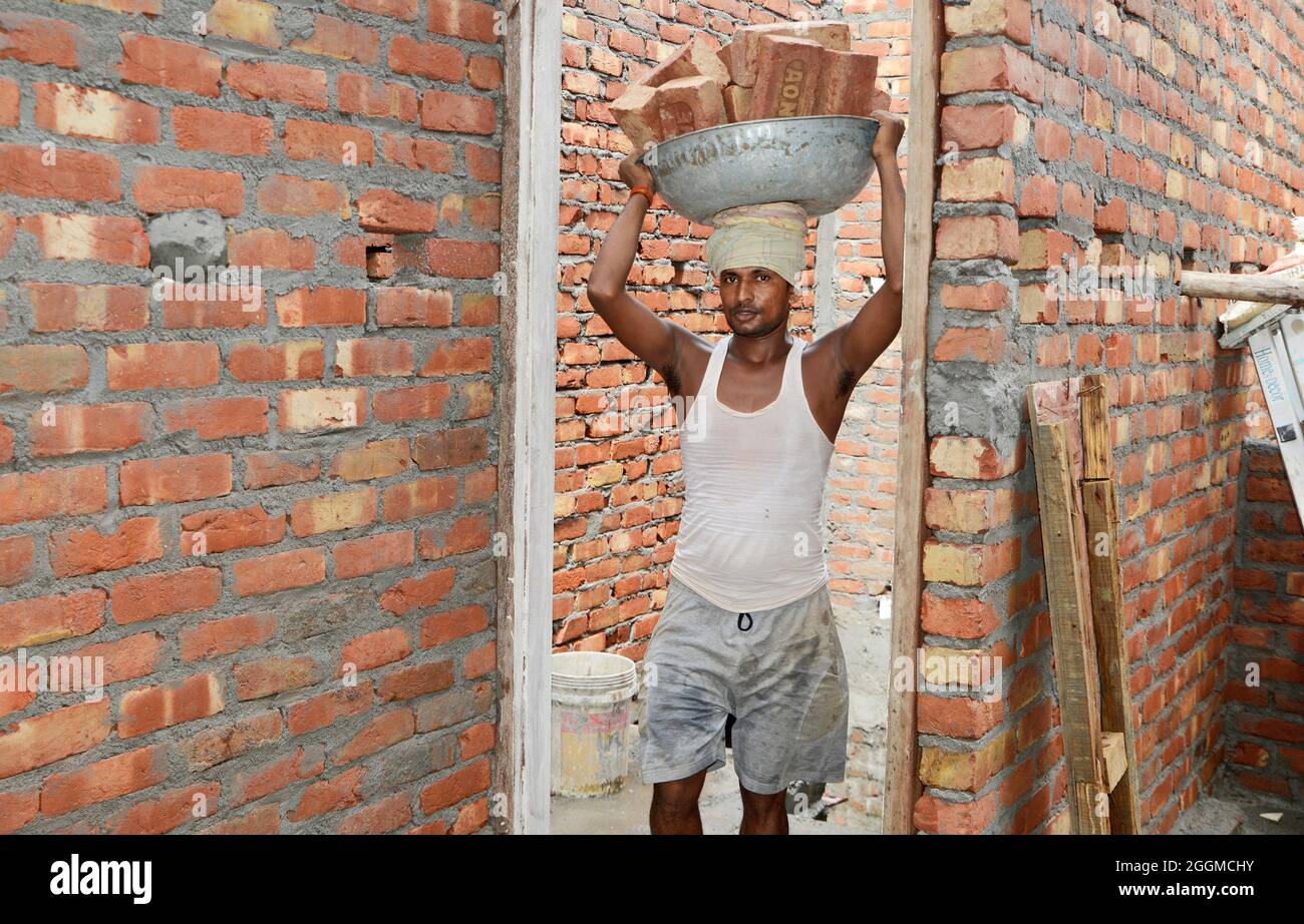 Labor carrying brick on head at construction site Stock Photo - Alamy