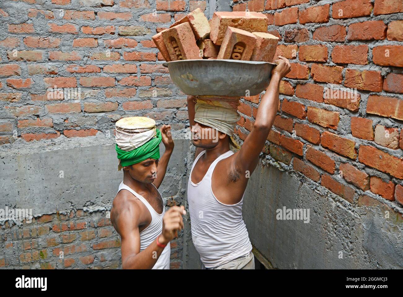 Labor carrying brick on head at construction site Stock Photo - Alamy
