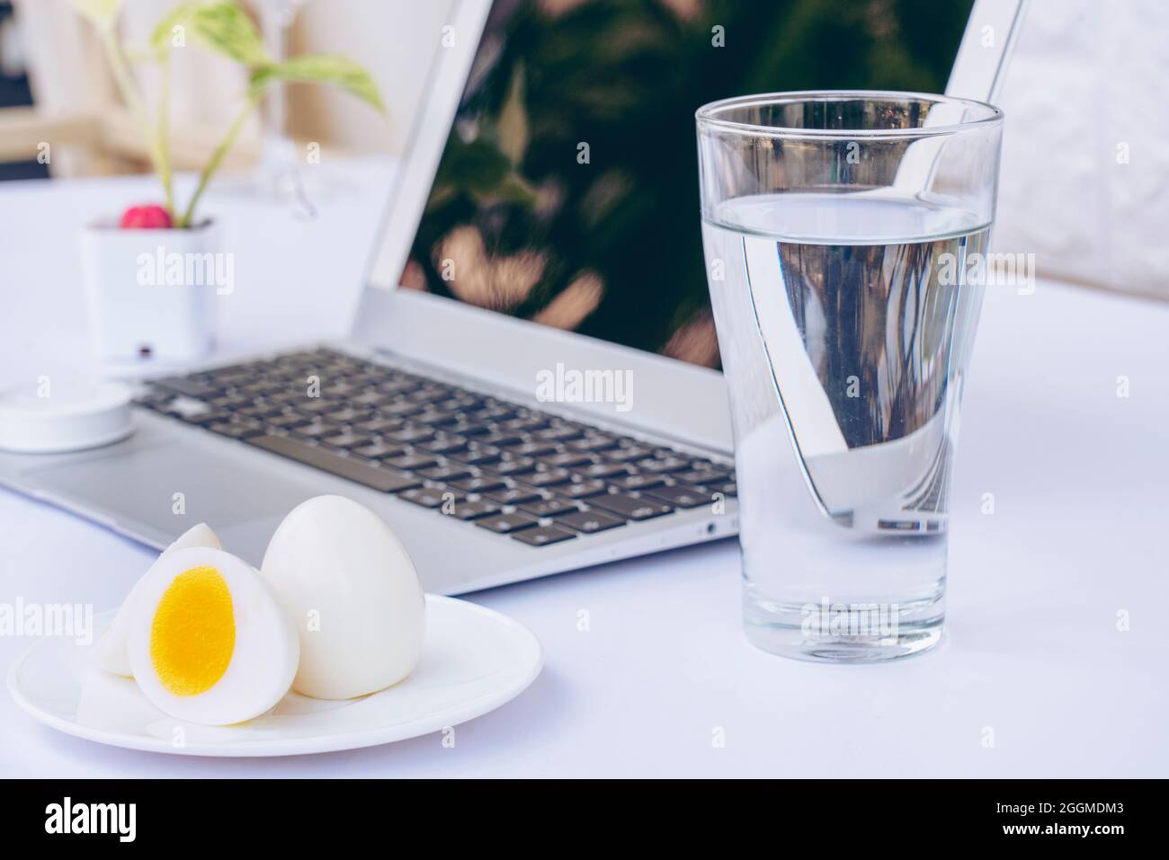 Glass of mineral water with boiled eggs and laptop computer isolated on ...