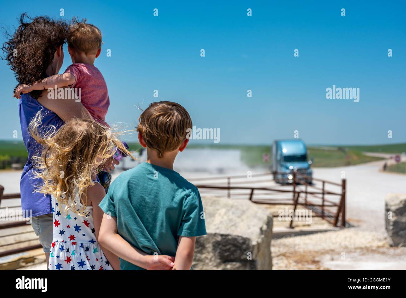 Mother and children looking into the distance while a semi truck comes ...