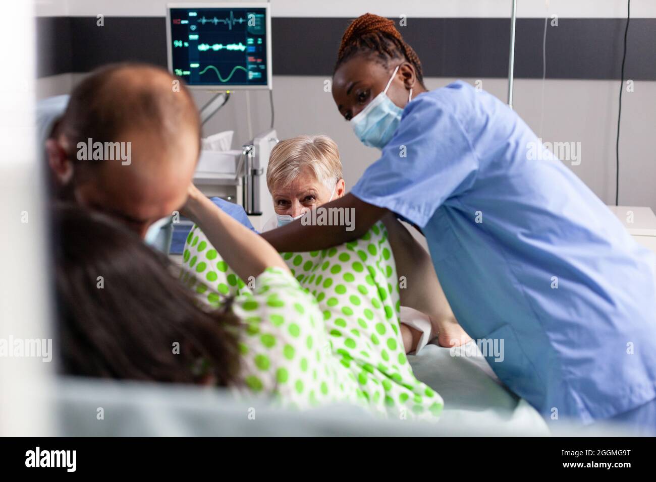 Close up of multi ethnic medical team delivering child in hospital ward ...