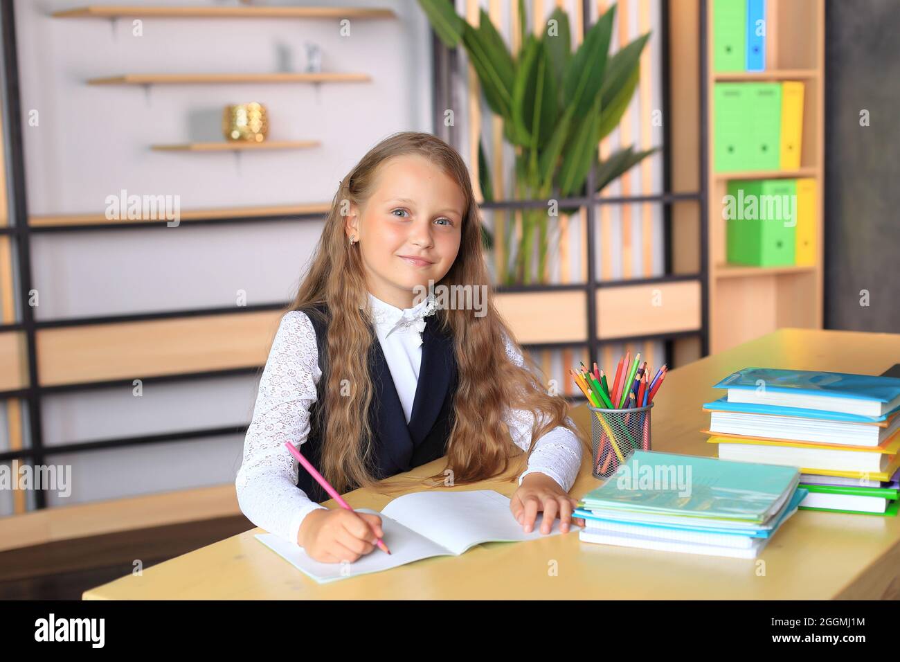 The schoolgirl sits over notebooks. The girl writes in a school ...