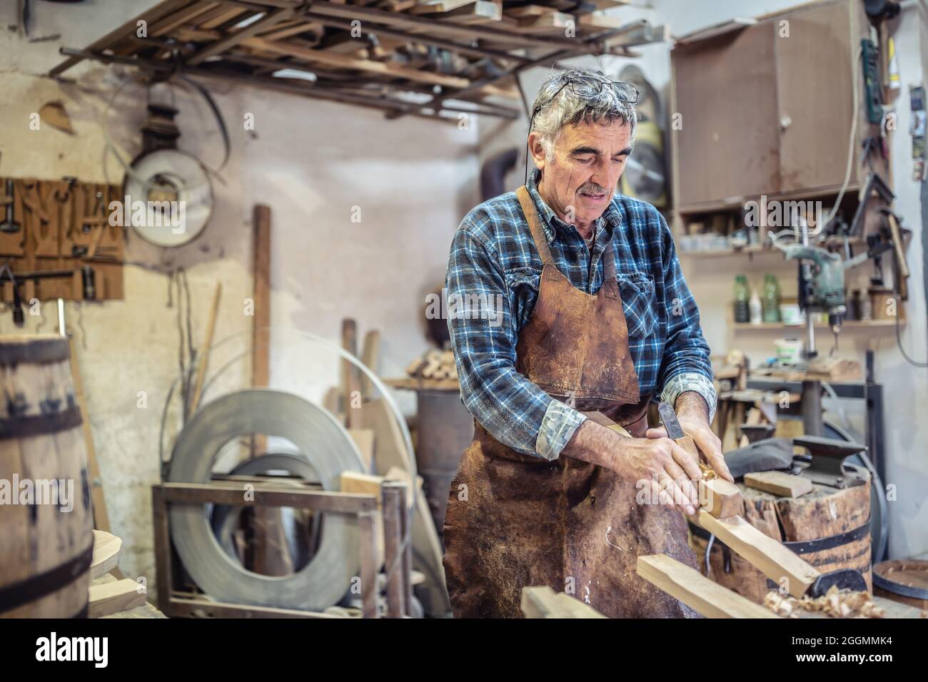 Old-fashioned way of processing wood as aged carpenter holds tools to ...