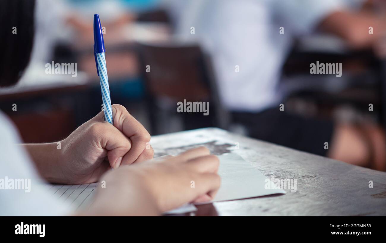 Students writing and reading exam answer sheets exercises in classroom ...