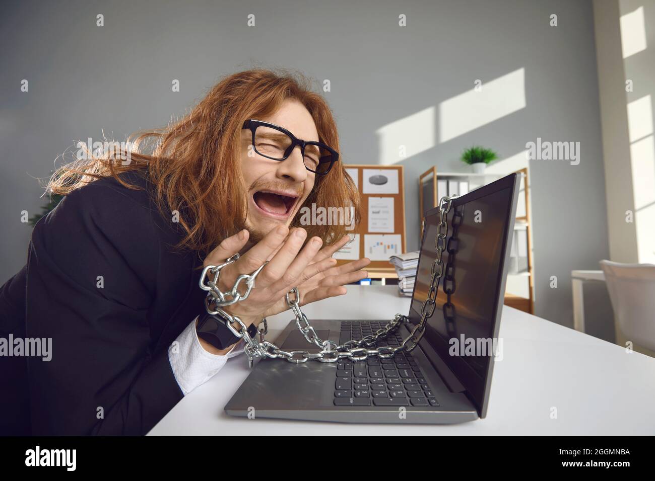 Tired office worker sitting chained to laptop computer and crying ...