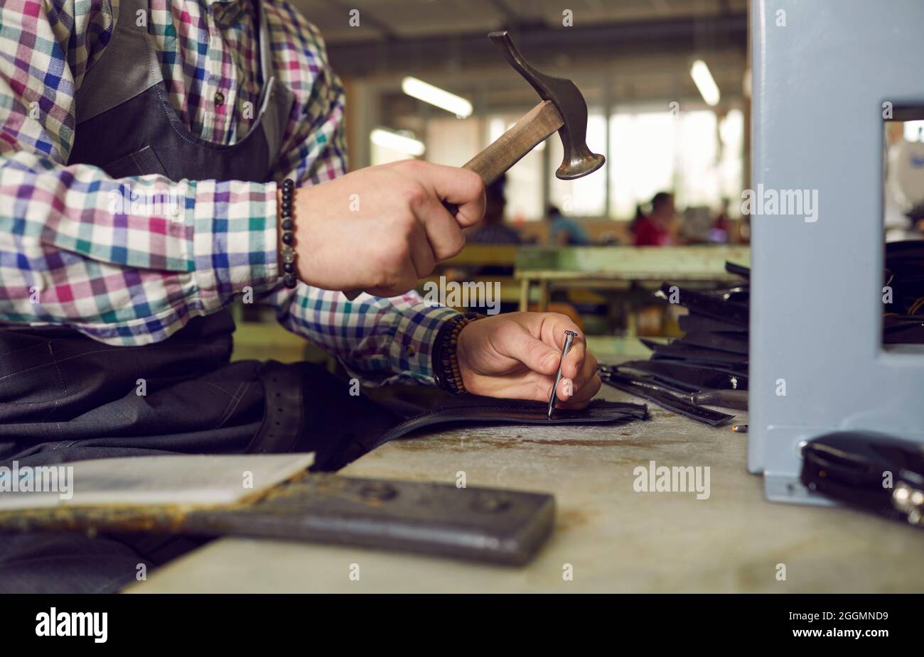 Shoe factory worker sitting at table, making new leather boots and ...