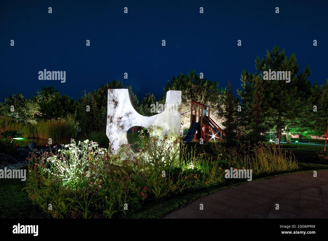 Summer night view of green park with illuminated children playground ...