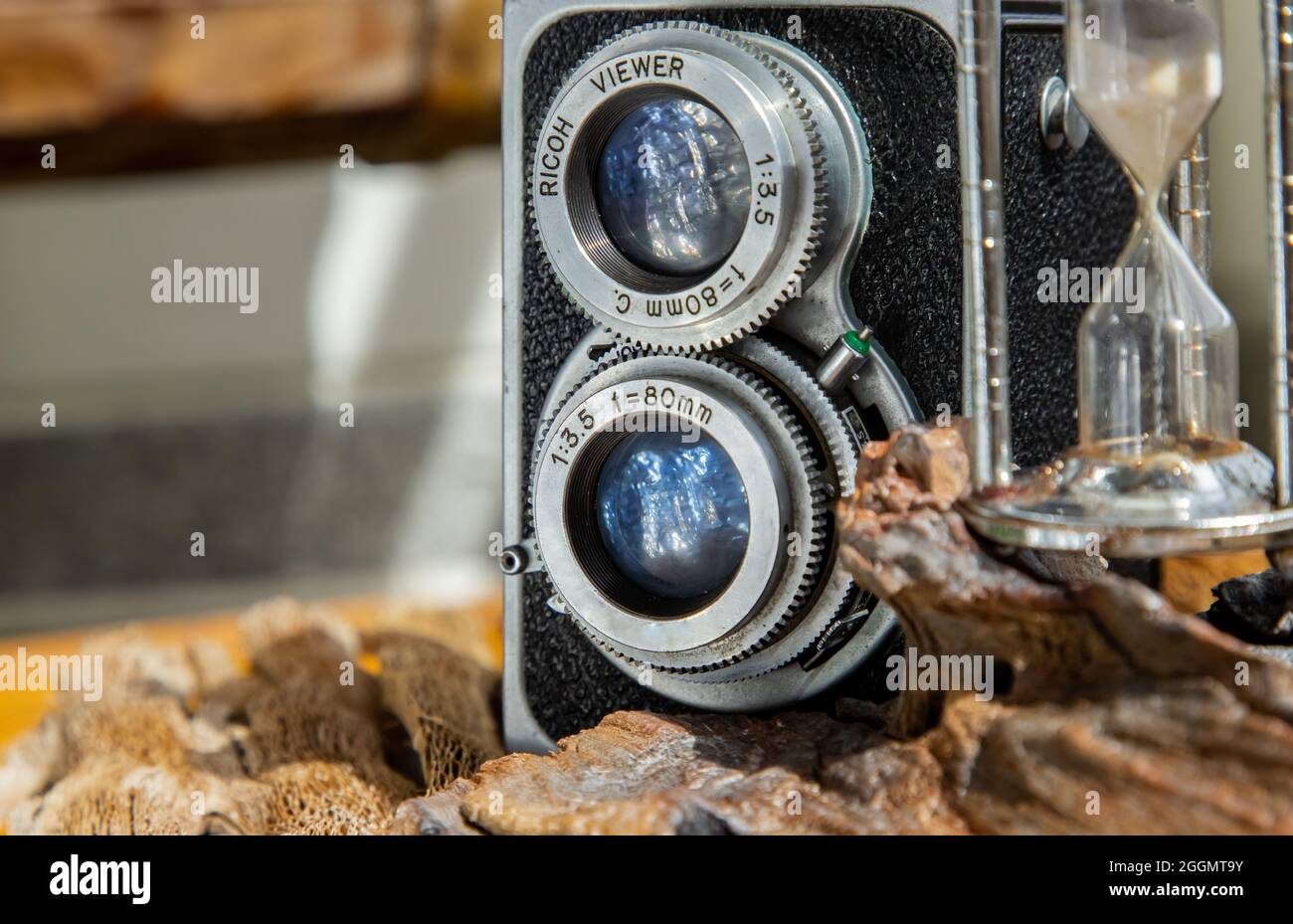 Vintage two lens photo camera with Hourglass on wooden background. An ...