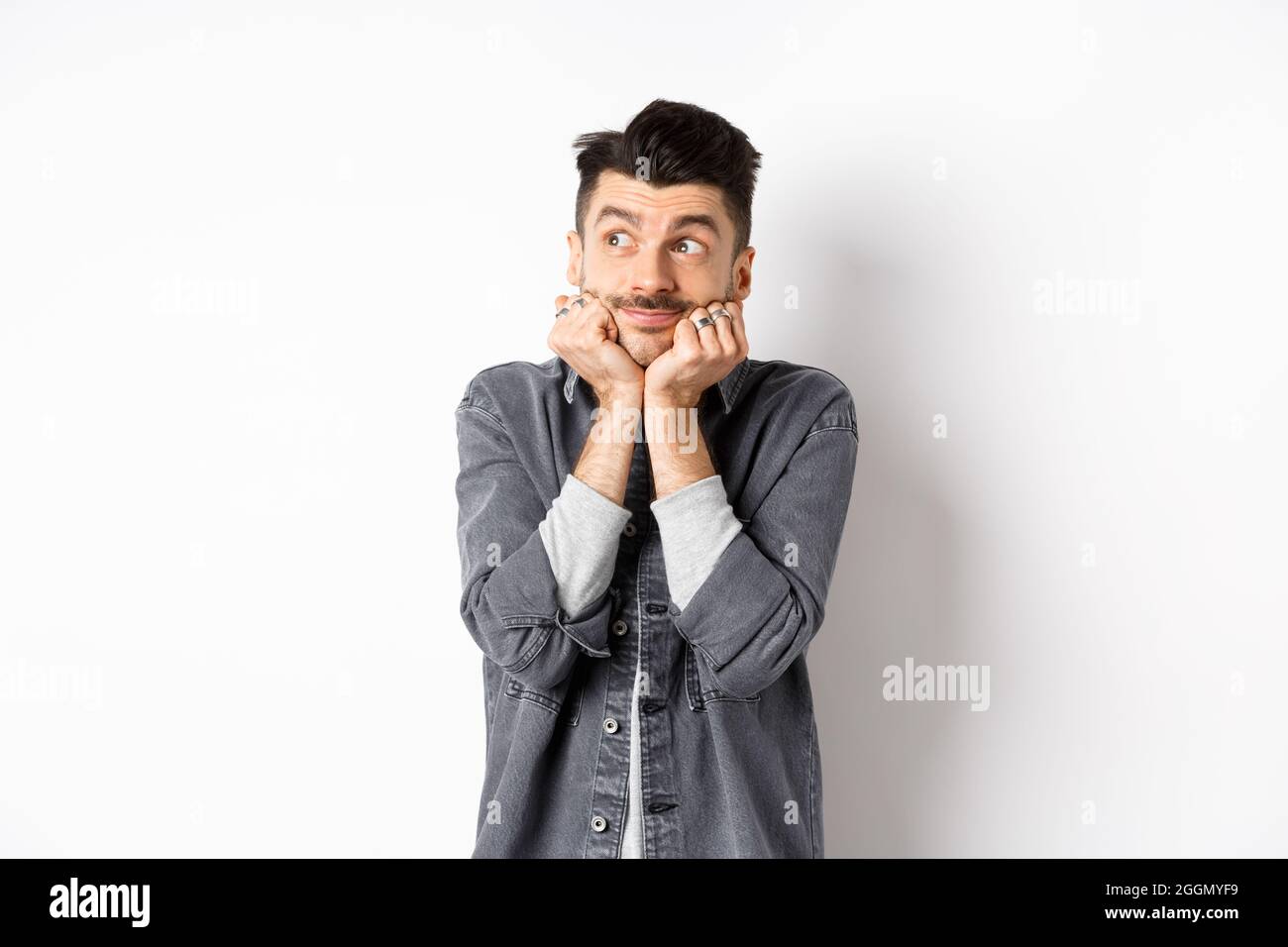 Excited cute young man look dreamy at upper left corner, waiting for ...