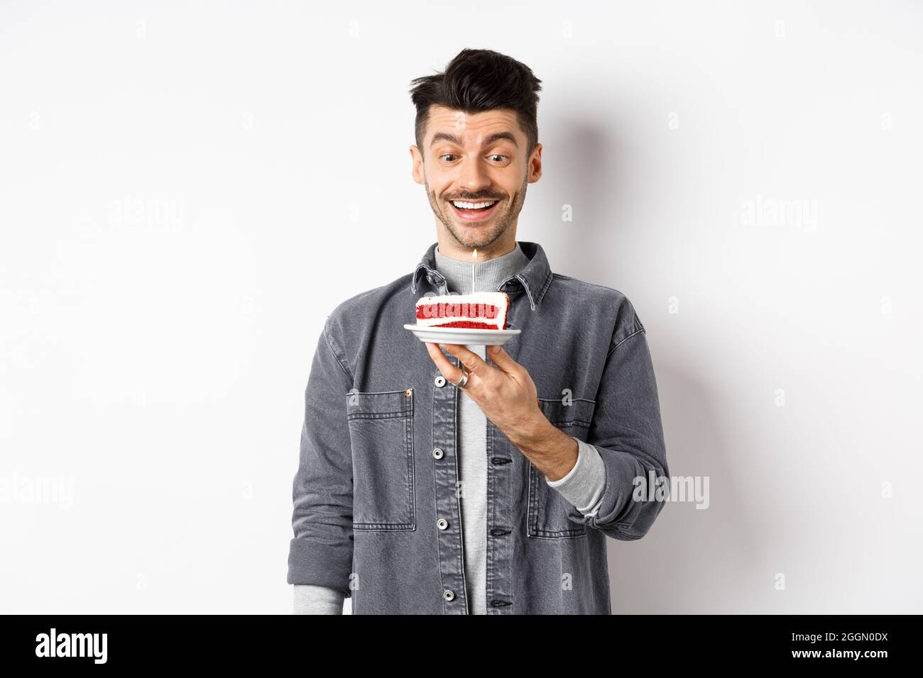 Happy birthday guy making wish on b-day cake, smiling and looking at ...