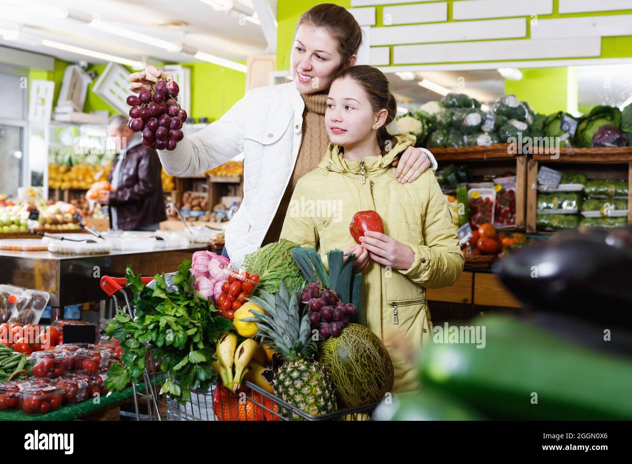 Cheerful preteen girl with young woman choosing fresh fruits Stock ...