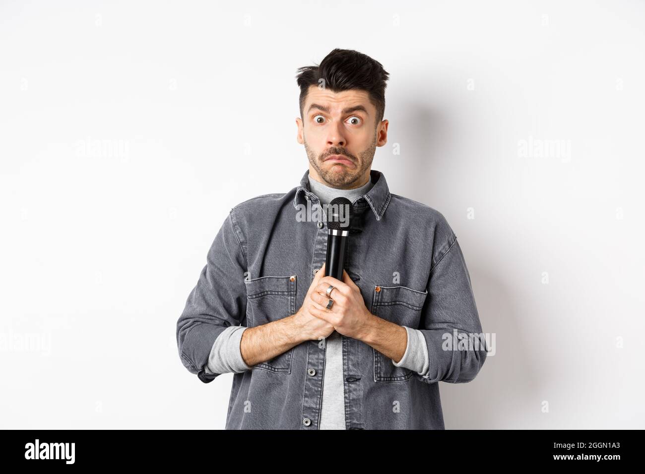 Nervous unconfident guy holding microphone and look indecisive, scared ...