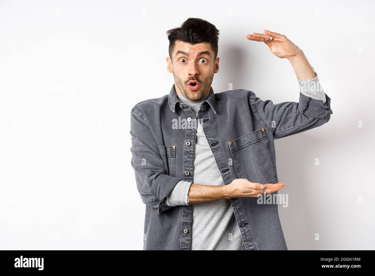 Cheerful guy smiling and showing big size, showing large thing and ...