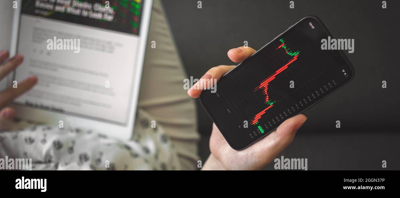 Woman checking stock market price chart on mobile phone while reading ...
