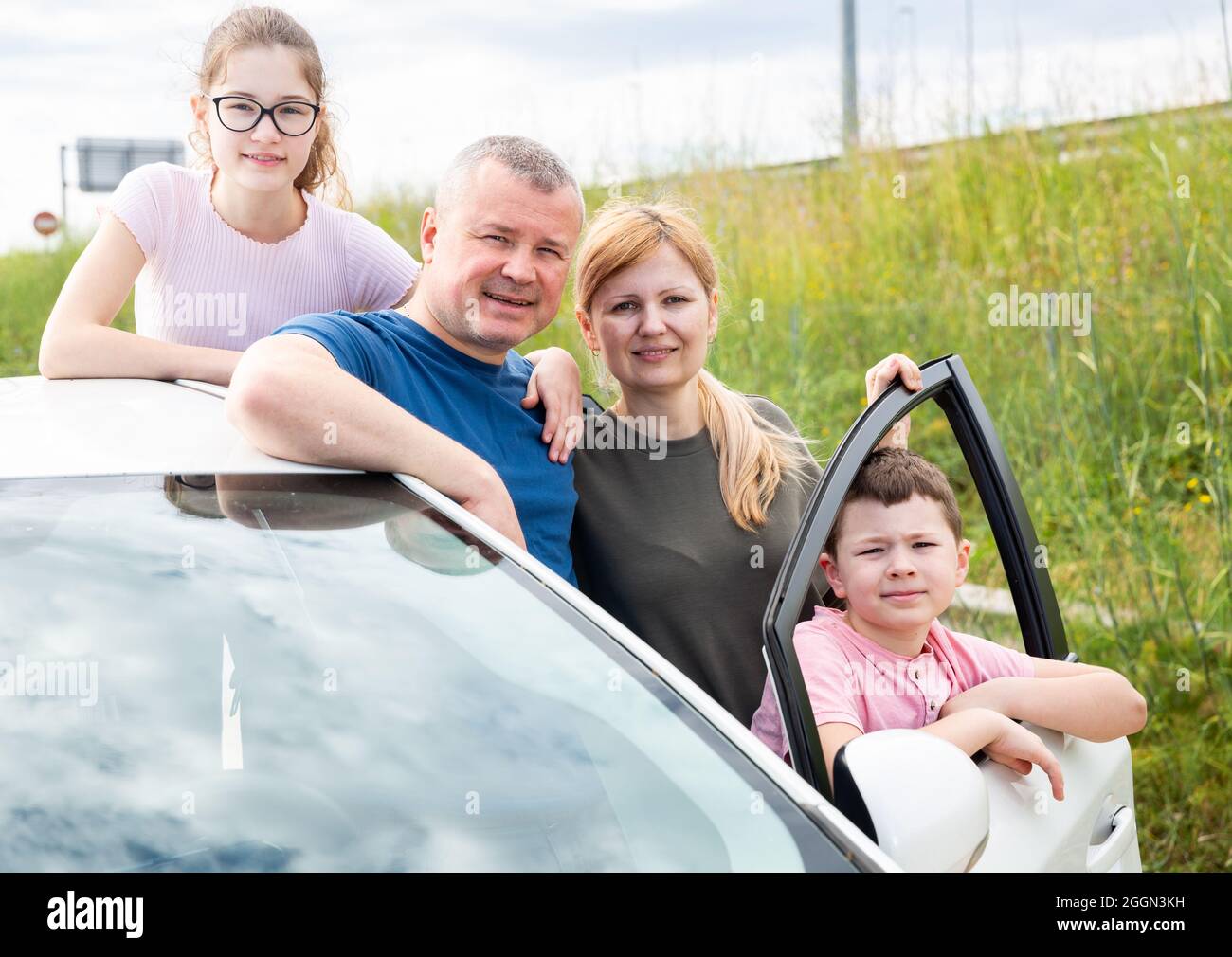 Happy parents with children posing together near car Stock Photo - Alamy