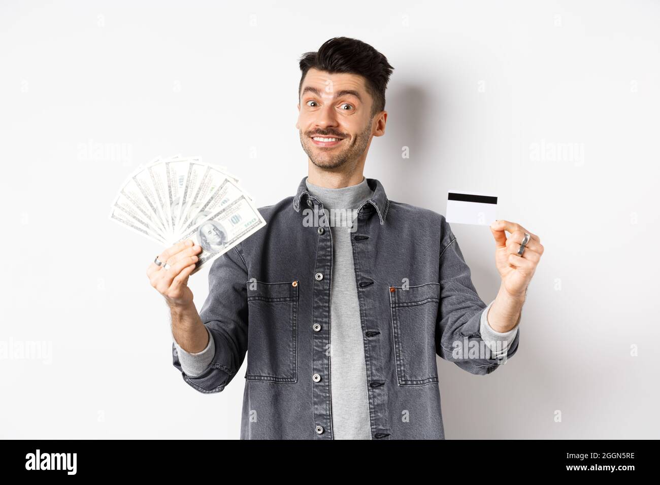 Happy guy showing plastic credit card and dollar bills, giving choice ...