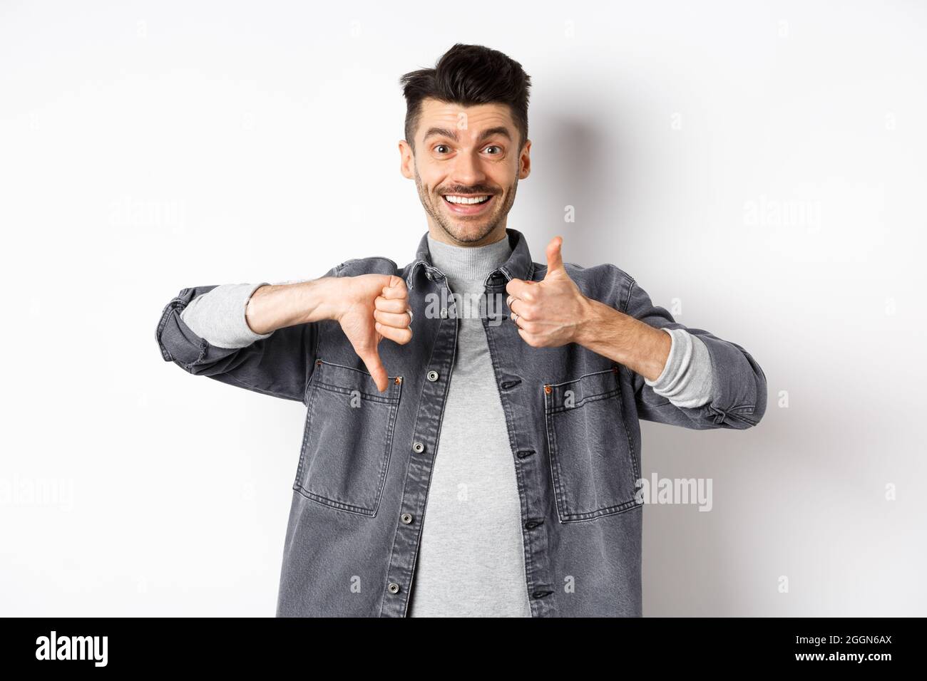 Happy smiling guy showing average gesture, thumbs down up, cant decide ...