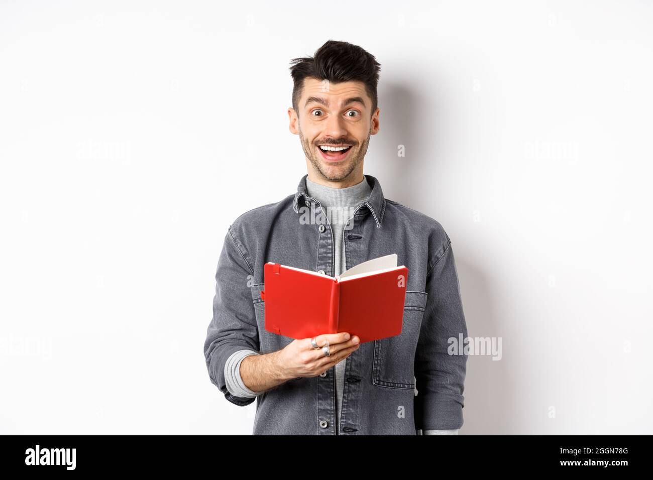 Hobbies and leisure. Happy young man reading planner, holding diary or ...