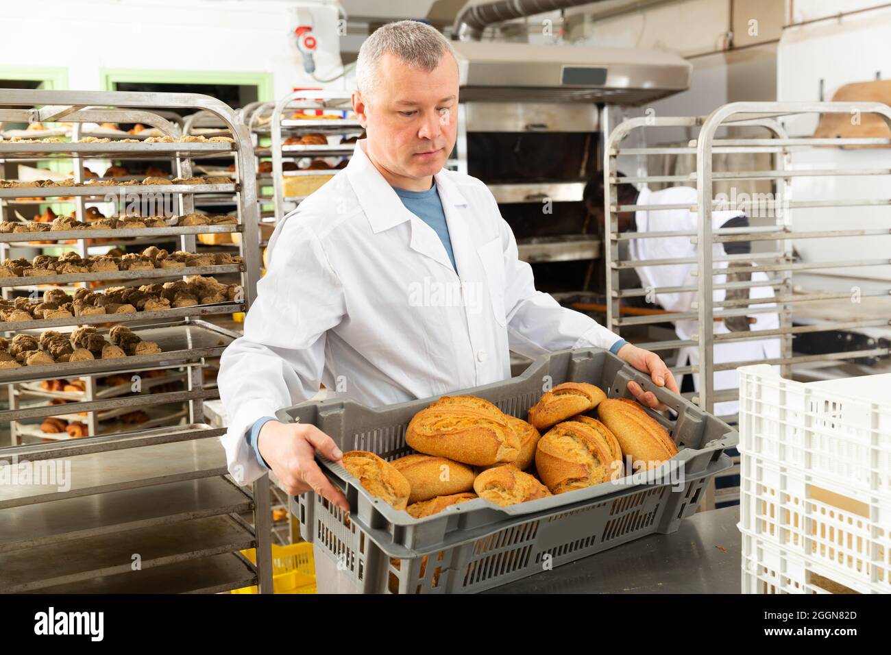 Bakery worker carrying box with loaves Stock Photo - Alamy
