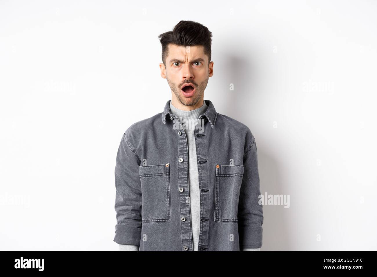 Shocked and offended man frowning, looking at camera with opened mouth ...