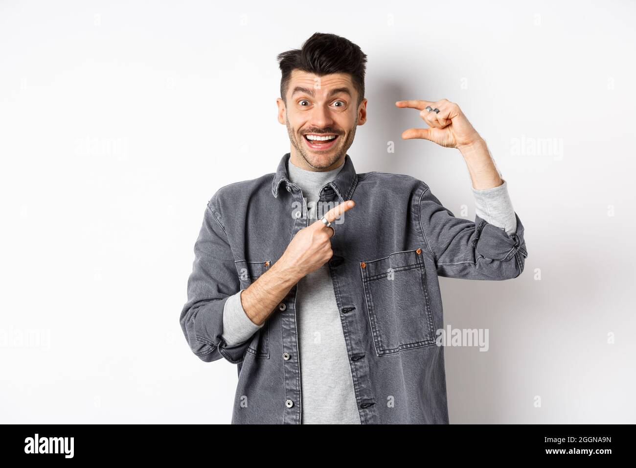 Excited man showing small size, pointing finger at little thing and ...
