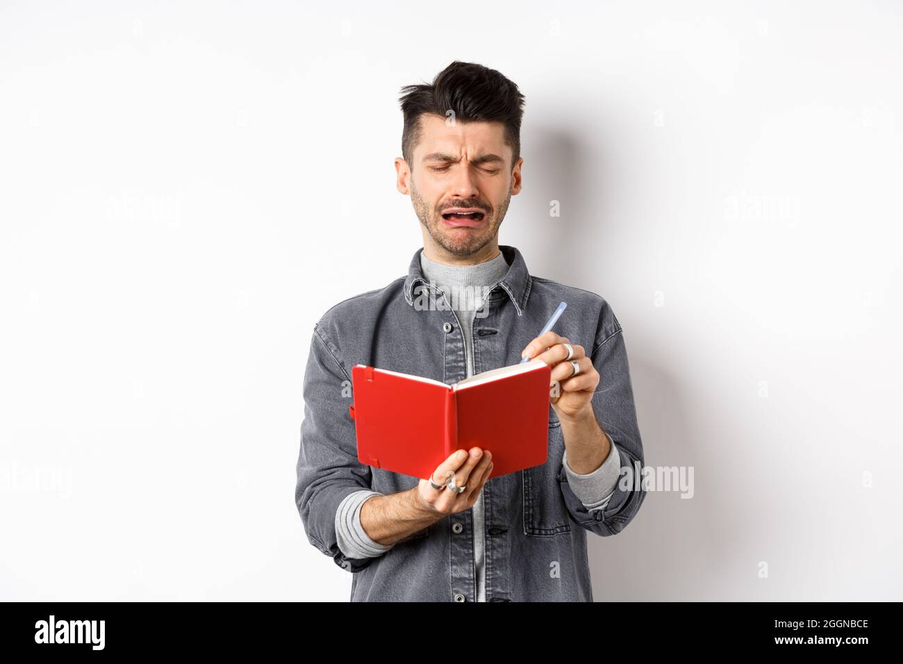 Sad crying guy writing in his diary with miserable face, look ...