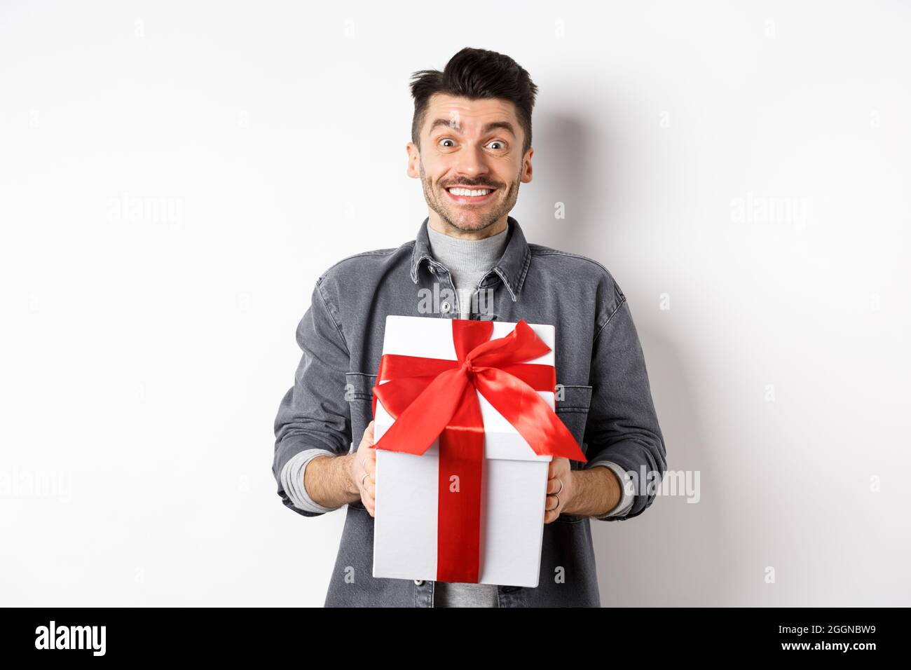 Cheerful caucasian guy holding surprise gift, receive present on ...