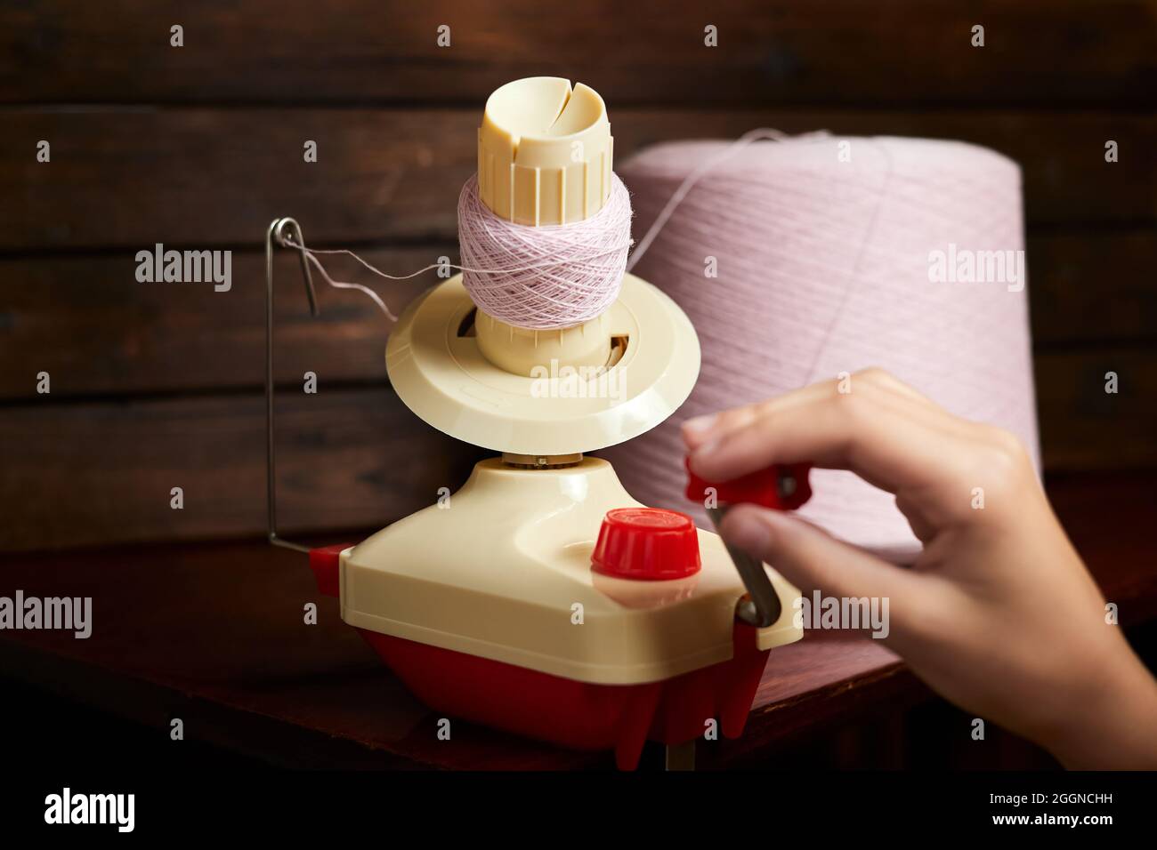 The girl rotates mechanical yarn winder or reel while rewinding thread ...