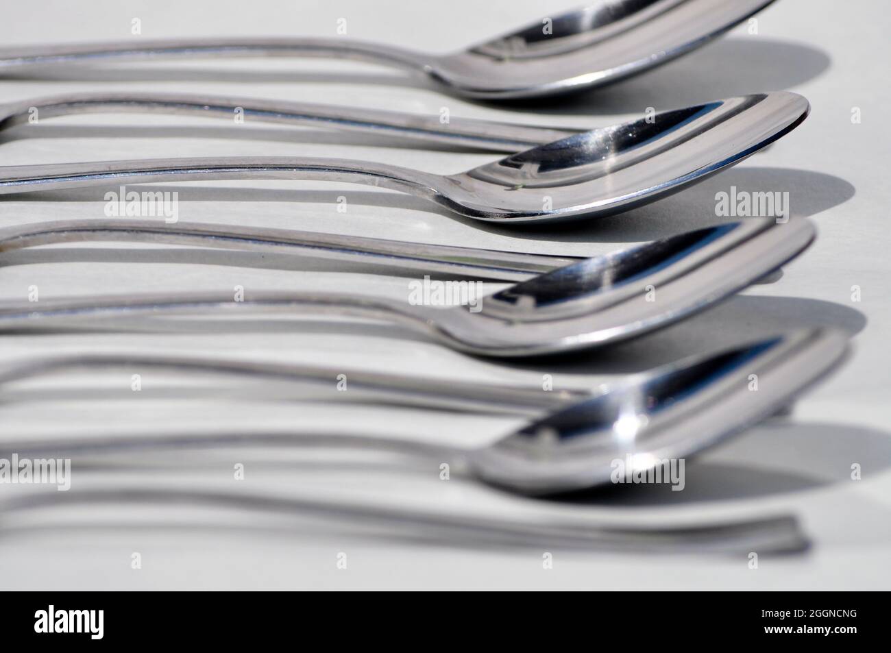 Stainless steel tablespoons arranged on a white background in a ...
