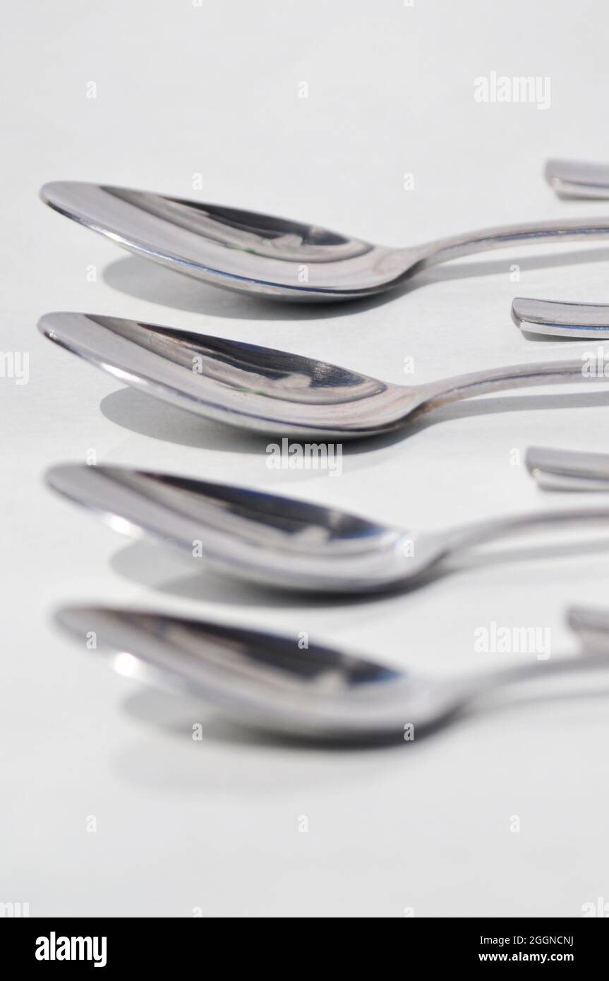 Stainless steel tablespoons arranged on a white background in a ...