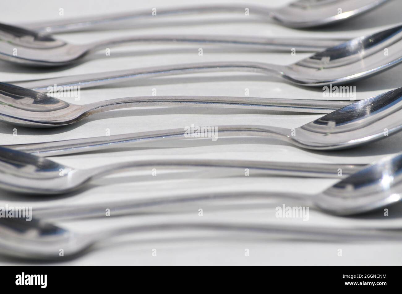 Stainless steel tablespoons arranged on a white background in a ...