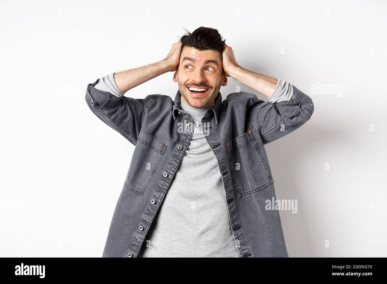 Excited young man looking relieved and happy aside, smiling and staring ...