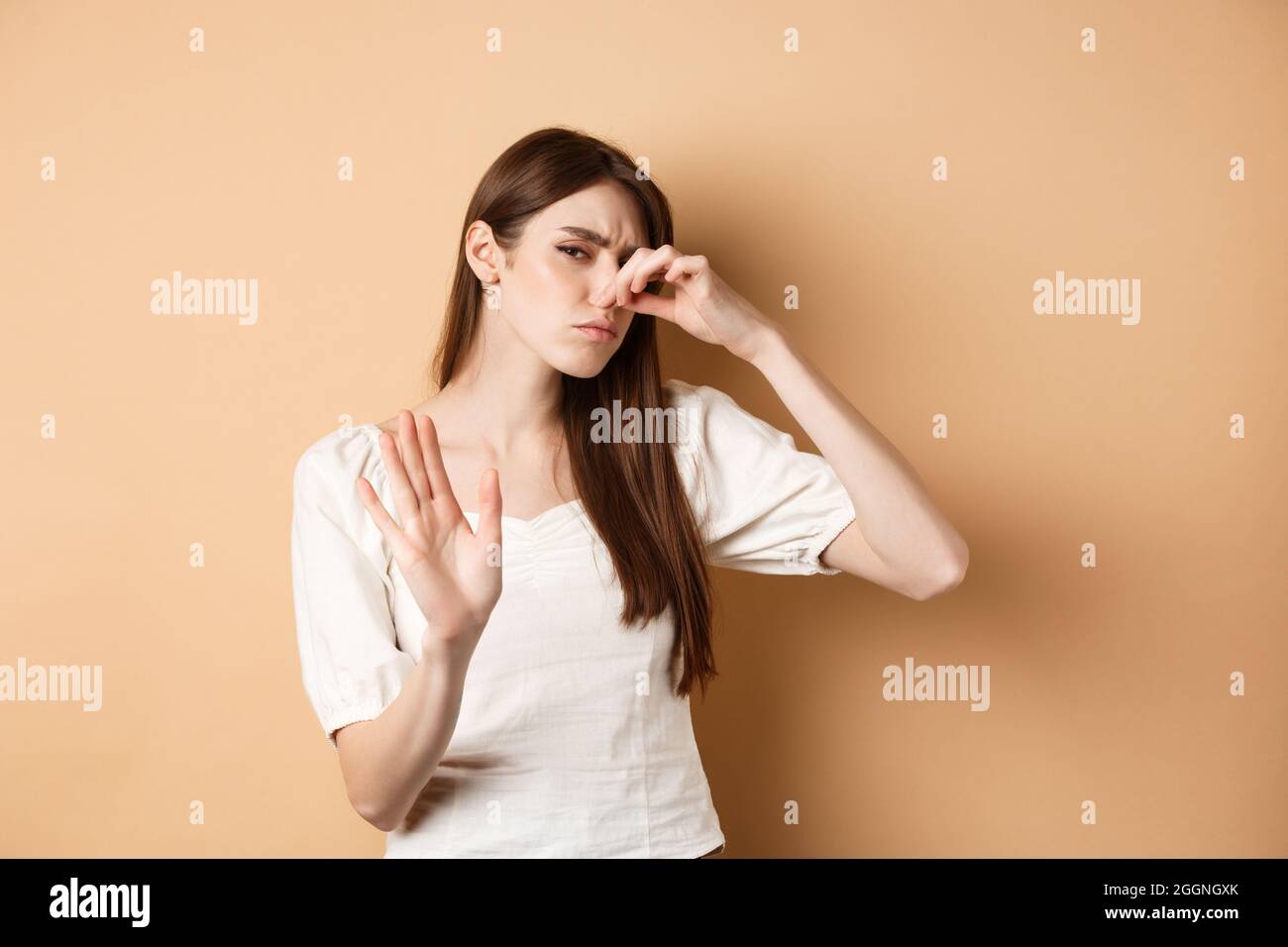 Displeased woman plug her nose from bad smell, showing stop gesture and ...