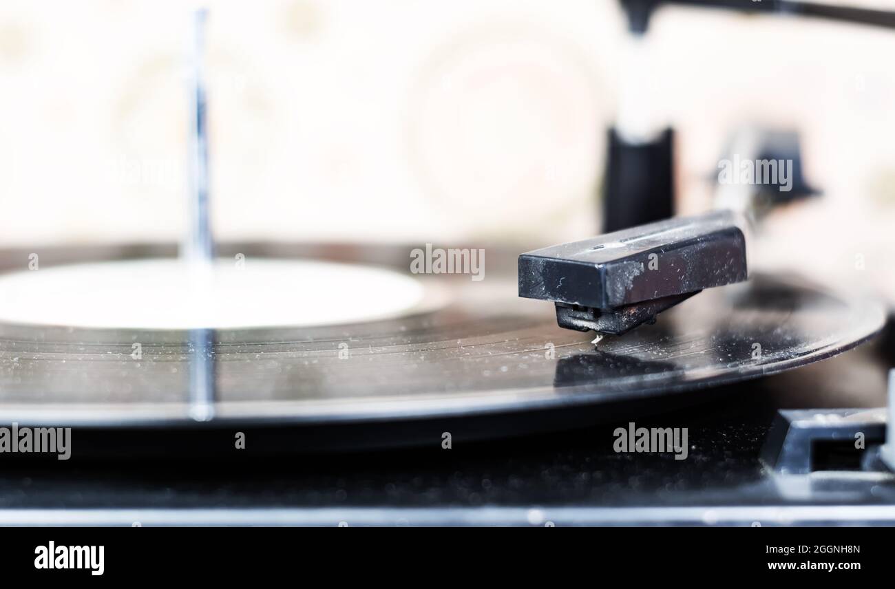 the needle of a turntable playing the tracks of a black vinyl record ...