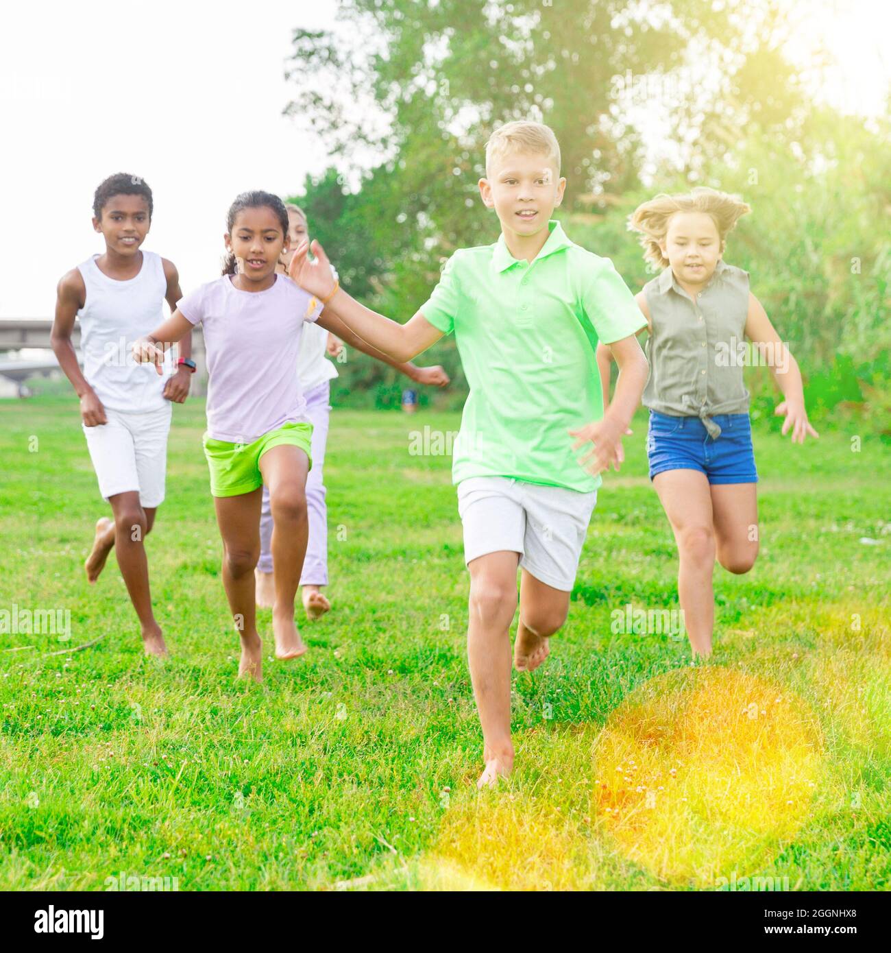 Multiracial group of cheerful tweens running together in city park ...