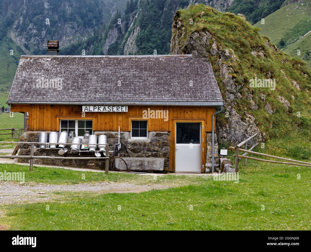 swiss alpine cheese dairy farm built in old style next to a rock wall ...