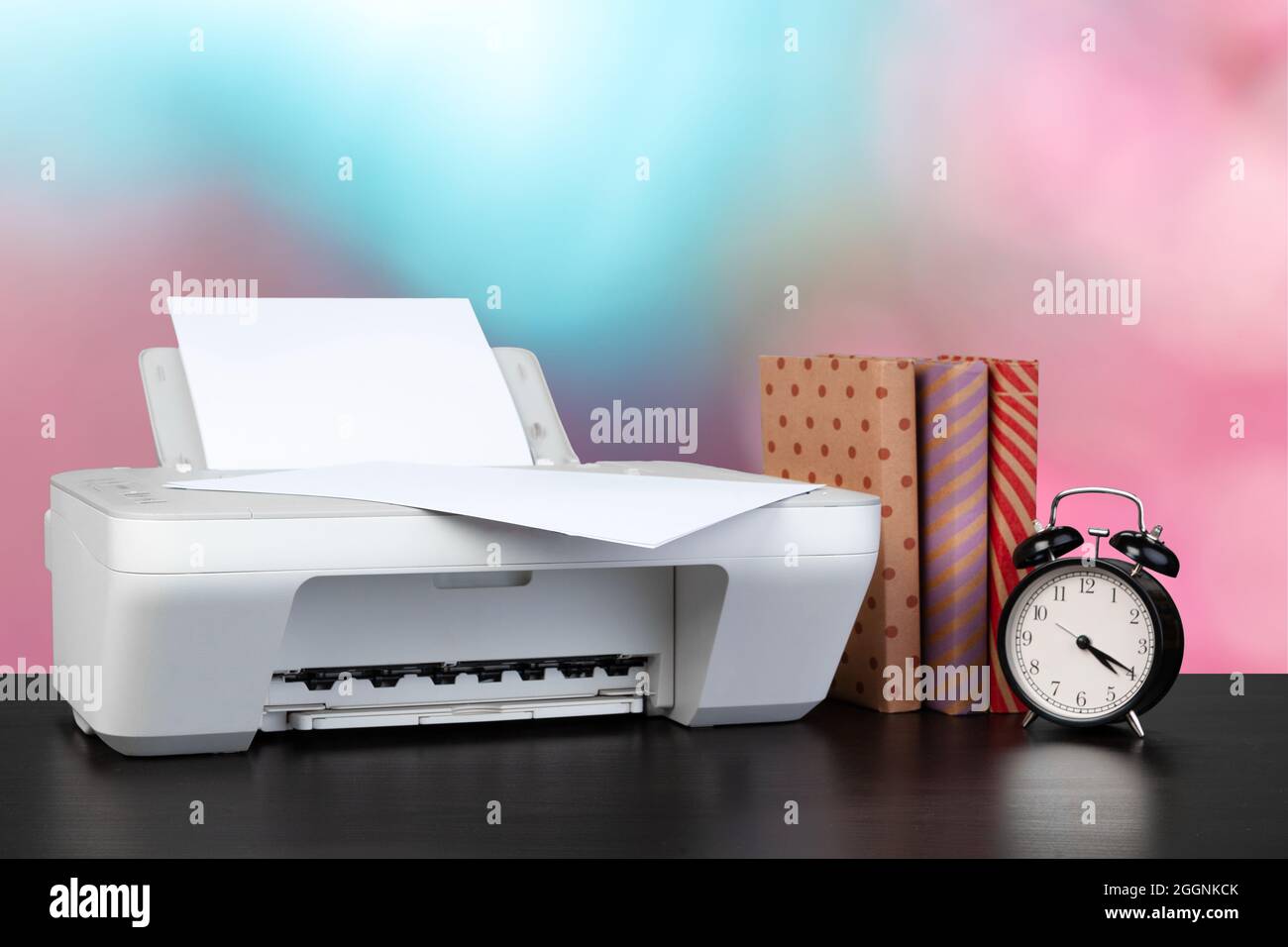 Compact home printer on desk with books against blurred background ...