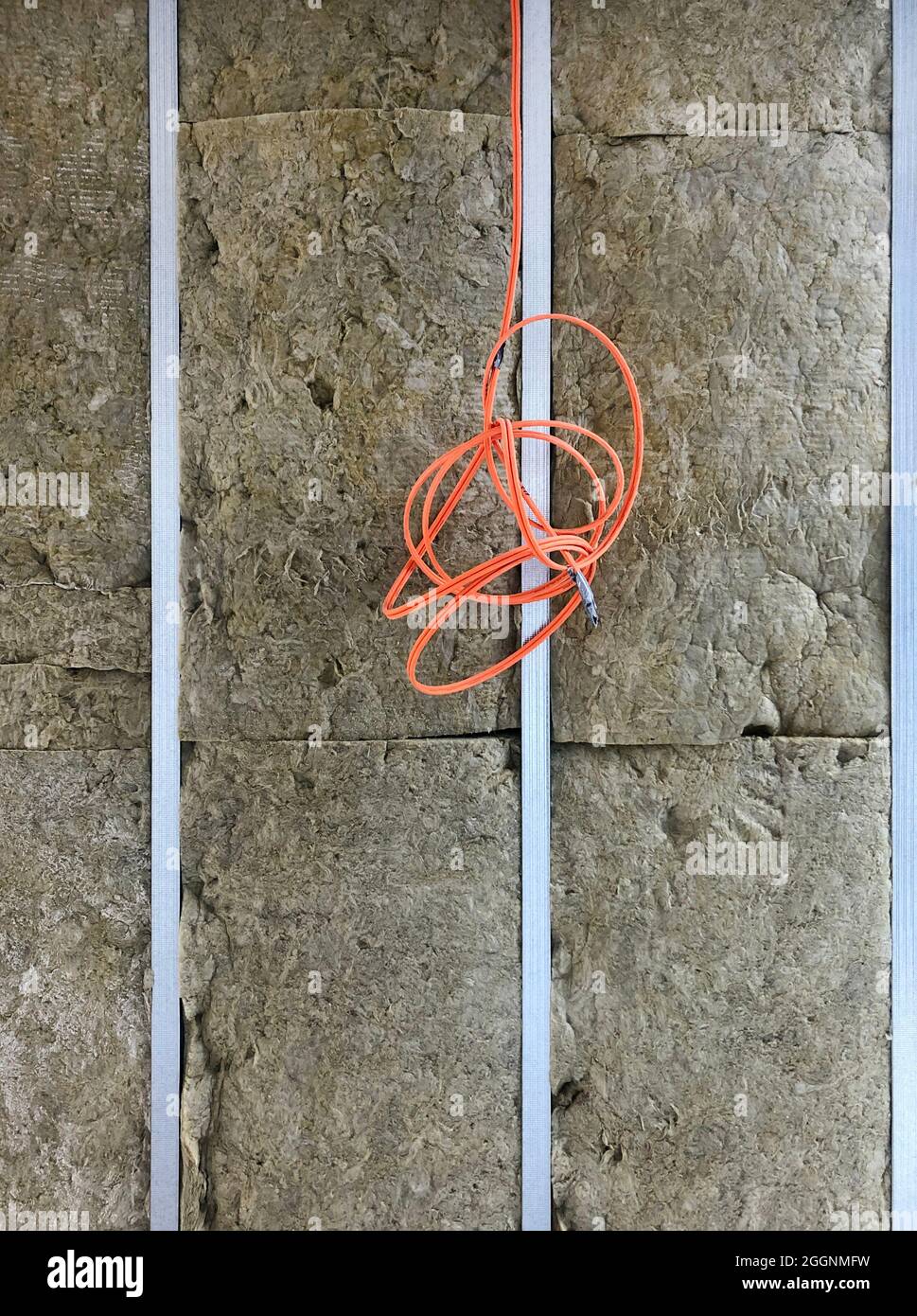 Open insulation and a cable hanging from a wall at a construction site ...